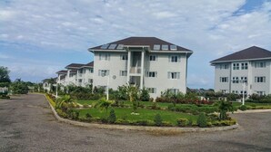 Uma fileira de edifícios de apartamentos modernos com um pátio central, cada um com varanda e um pequeno jardim.