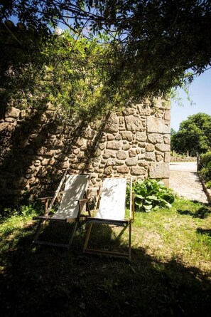 Paredes de pedra com um banco de madeira e uma lousa branca encostada.