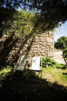 Paredes de pedra com um banco de madeira e uma lousa branca encostada.
