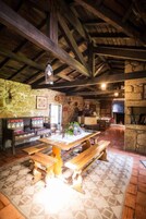 Um interior rústico com vigas de madeira expostas, paredes de pedra e uma lareira.