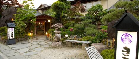 Um edifício japonês tradicional com um caminho de pedra que leva a uma entrada de madeira.