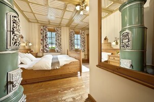 Quarto com cama de madeira, fogão verde e um espelho grande refletindo o ambiente.