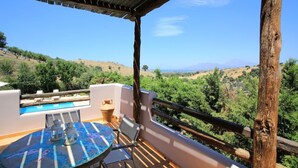 Terraço com piscina, área de estar externa e vista para uma paisagem montanhosa.