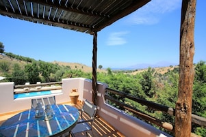 Terraço com piscina, área de estar externa e vista para uma paisagem montanhosa.