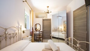 Um quarto com cama, escrivaninha, cadeira, espelho e guarda-roupa.