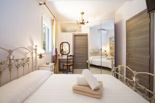 Um quarto com cama, escrivaninha, cadeira, espelho e guarda-roupa.