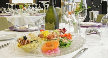 Uma mesa de jantar posta com pratos de comida, copos de vinho e uma garrafa de vinho.