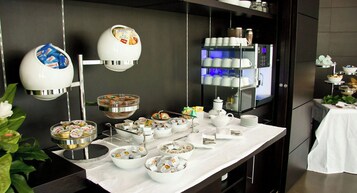 Uma mesa de buffet com diversos alimentos e uma máquina de café.