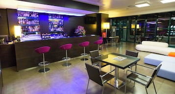 Uma área de bar com balcão, banquetas e um espaço de estar com mesa e cadeiras.