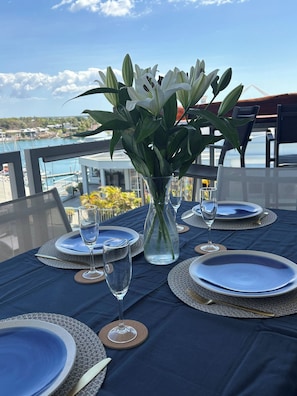 Mesa posta para refeição com vista para o porto e barcos.