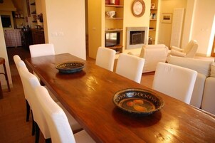 Uma sala de jantar com mesa de madeira, cadeiras brancas e duas tigelas decorativas.