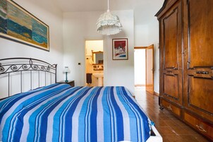 Quarto com cama, guarda-roupa, luminária pendente e um quadro na parede.