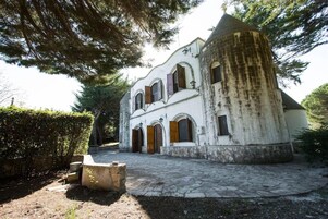 Um edifício histórico com fachada de pedra, janelas em arco e uma torre redonda.