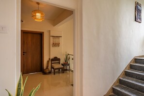 Uma escadaria que leva a um patamar com uma porta de madeira e um lustre.
