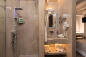 Casa de banho moderna com chuveiro, toucador com espelho, secador de cabelo e toalhas.