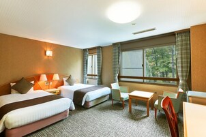Quarto de hotel com duas camas, uma escrivaninha, uma cadeira e uma janela com cortinas.