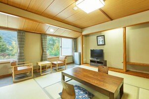 Um quarto tradicional japonês com tatames, uma mesa de madeira baixa e uma televisão.