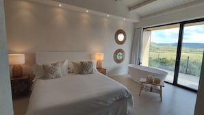 Um quarto espaçoso com uma cama grande, uma banheira e vista para o exterior.