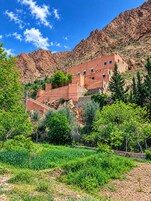 Um edifício tradicional com vários andares, rodeado por vegetação exuberante e um cenário montanhoso.