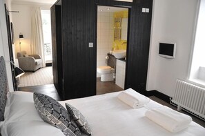 Quarto de hotel com cama, banheiro e televisão.