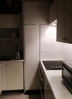 Uma cozinha compacta com fogão embutido, chaleira e micro-ondas.