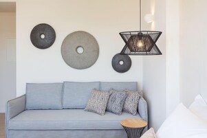 Uma sala de estar moderna com um sofá cinzento, almofadas estampadas e uma pequena mesa redonda.