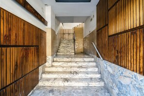 Escadaria de mármore com degraus que levam a um patamar, ladeada por painéis de madeira em ambos os lados.