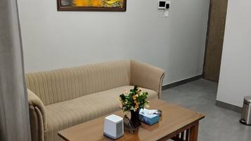 Uma sala de estar moderna com um sofá bege, uma mesa de centro de madeira e uma pintura de uma paisagem com um veado.