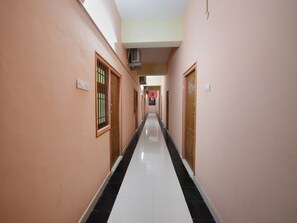 Um corredor com portas em ambos os lados, piso ladrilhado e unidade de ar condicionado no teto.
