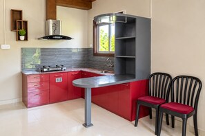 Uma cozinha moderna com armários vermelhos, fogão de aço inoxidável e ilha integrada com assentos.