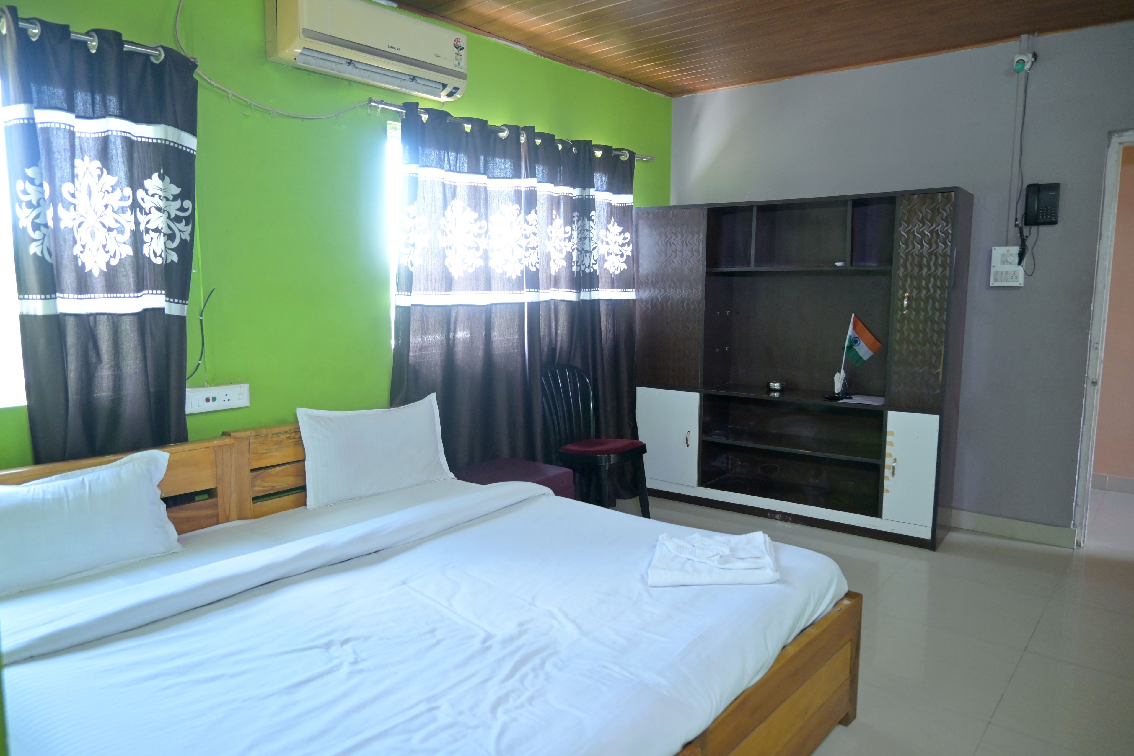 Quarto de hotel com cama, guarda-roupa, escrivaninha e ar condicionado.