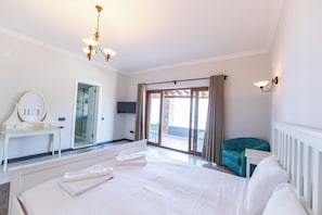 Quarto de hotel com cama, escrivaninha, espelho, televisão e vista para o exterior.