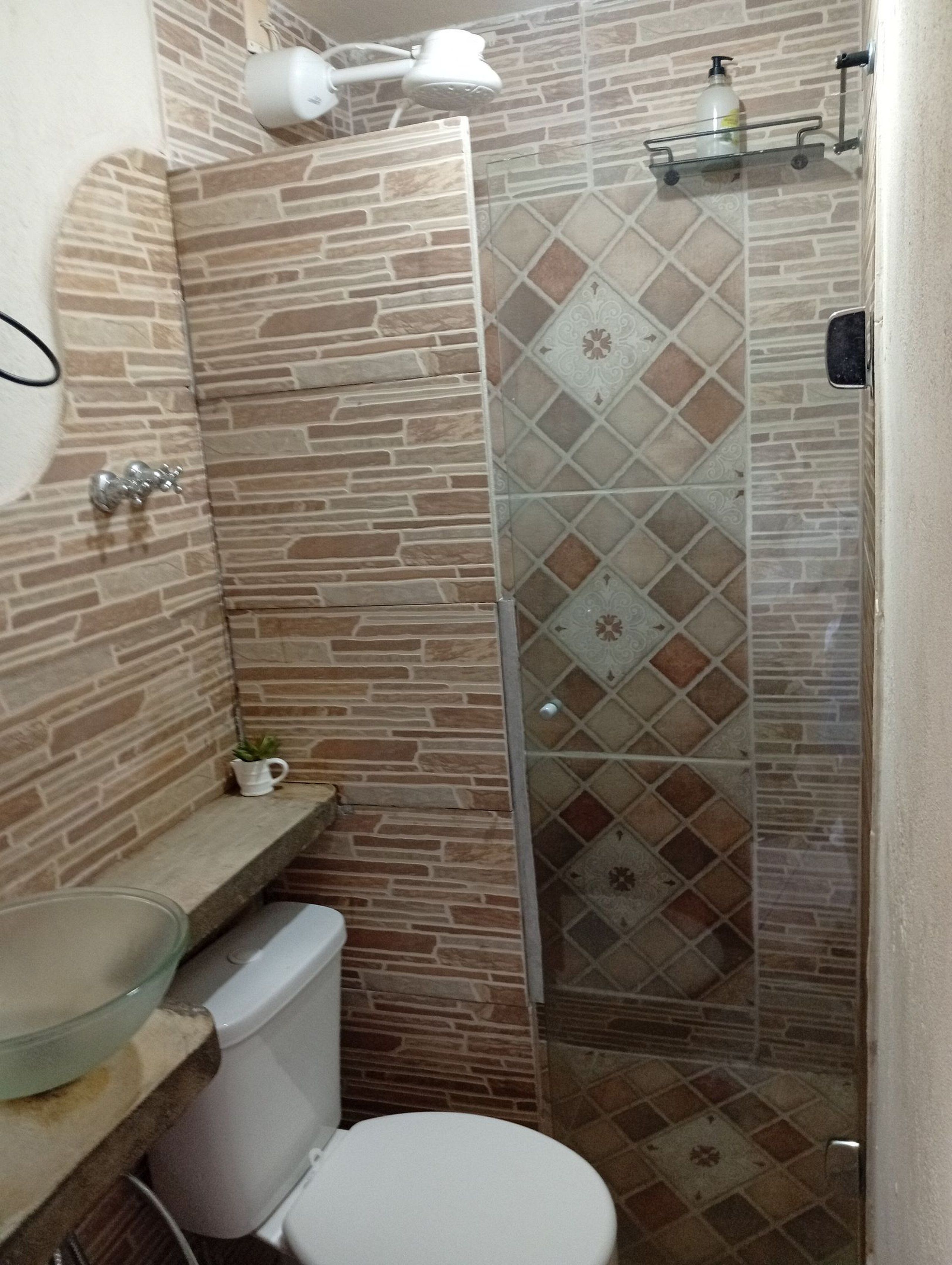 Casa de banho com chuveiro, sanita e lavatório.