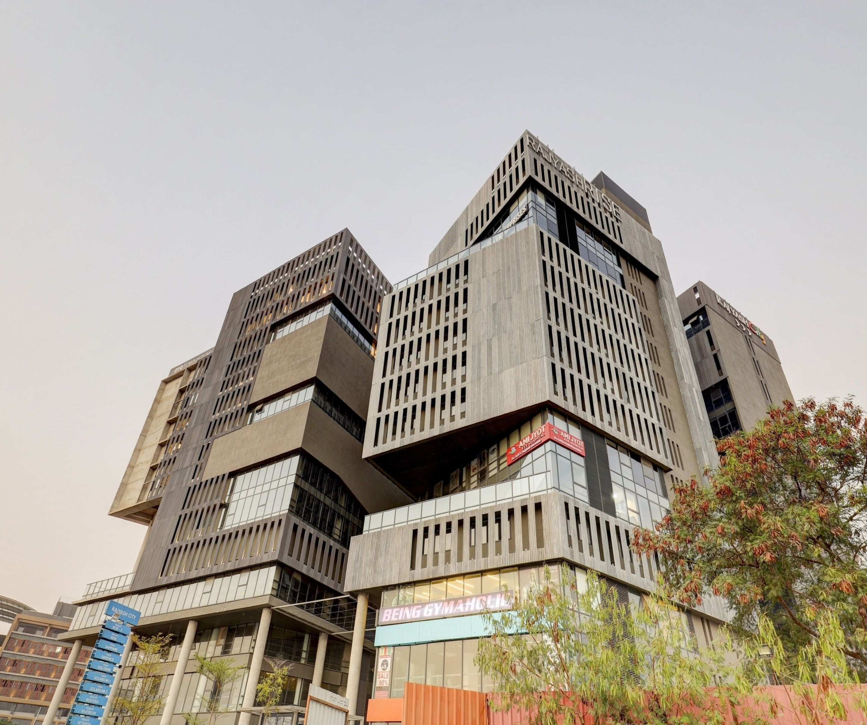 Edifício de vários andares com um design angular distinto, exibindo uma placa chamativa de uma academia.
