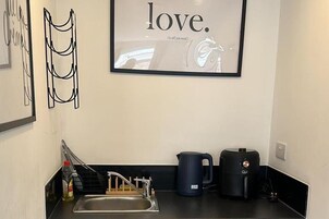 Cozinha com pia, chaleira e cafeteira.