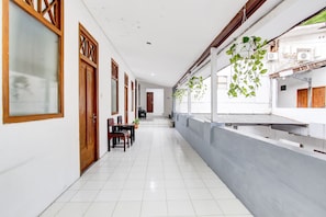 Um corredor com portas de madeira, uma sala de jantar com mesa e cadeiras, e plantas penduradas.