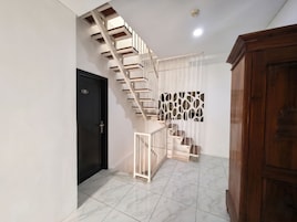 Uma escadaria moderna com corrimão branco, uma porta preta com um número e uma parede com padrão.