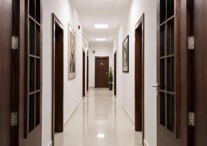 Um corredor com portas de madeira, uma planta em vaso e quadros nas paredes.