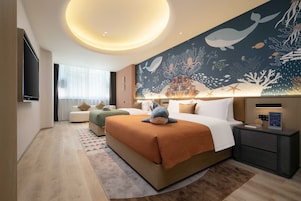 Quarto de hotel com cama grande, mesa de cabeceira, painel na parede e televisão de tela plana.