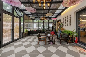 Um quarto amplo com piso xadrez, janelas grandes e um espaço de estar com cadeiras e mesa.