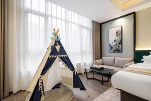 Quarto de hotel com cama, sofá, mesa pequena e um tipi decorativo.