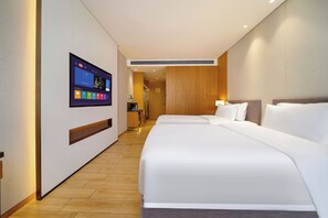 Quarto de hotel com uma cama grande, televisão fixada na parede e piso de madeira.