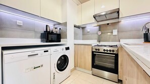 Cozinha moderna com máquina de lavar Siemens, micro-ondas LG, exaustor Bosch e forno de aço inoxidável.