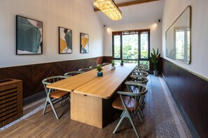 Sala de conferência com uma longa mesa de madeira, cadeiras de metal e arte abstrata nas paredes.