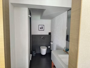 Casa de banho moderna com sanita, lavatório e espelho.