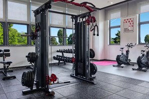 Uma academia com equipamentos de musculação, halteres e aparelhos de cardio.