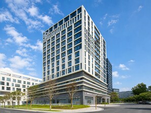 Um edifício moderno de hotel com vários andares, janelas amplas e telhado plano.