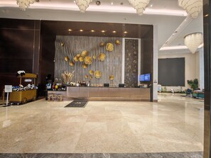 Uma área de recepção de hotel com balcão, bancada com brinquedos de pelúcia e parede decorativa com enfeites pendurados.