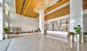 Um hall amplo com chão de mármore, balcão de recepção, área de estar e iluminação decorativa.