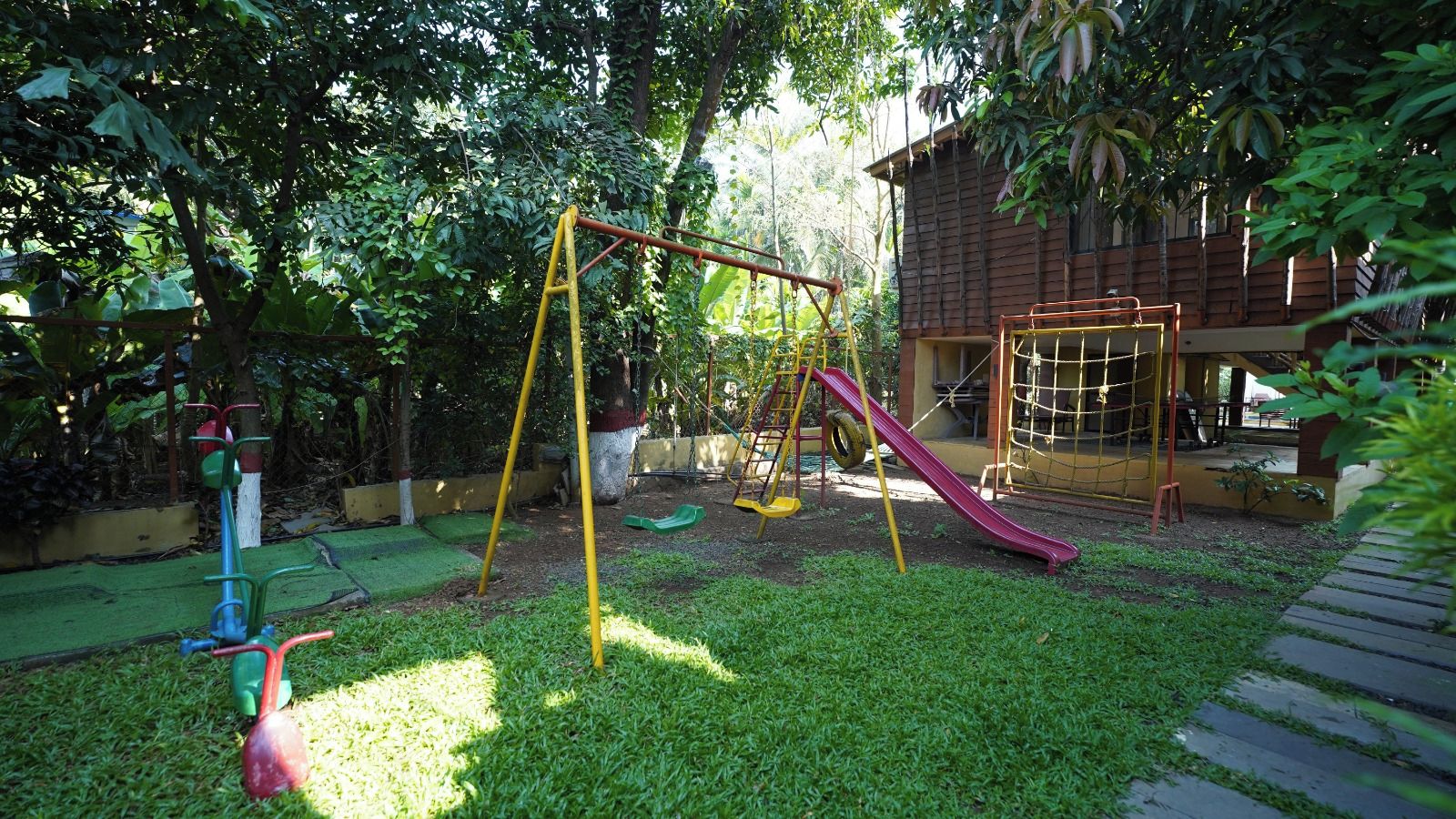 Um parquinho com balanços, escorrega e uma rede de escalada.